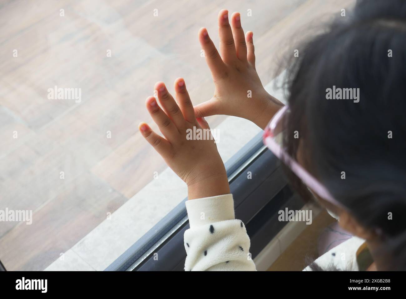 A childs hands are gently touching the glass, full of curiosity and ...