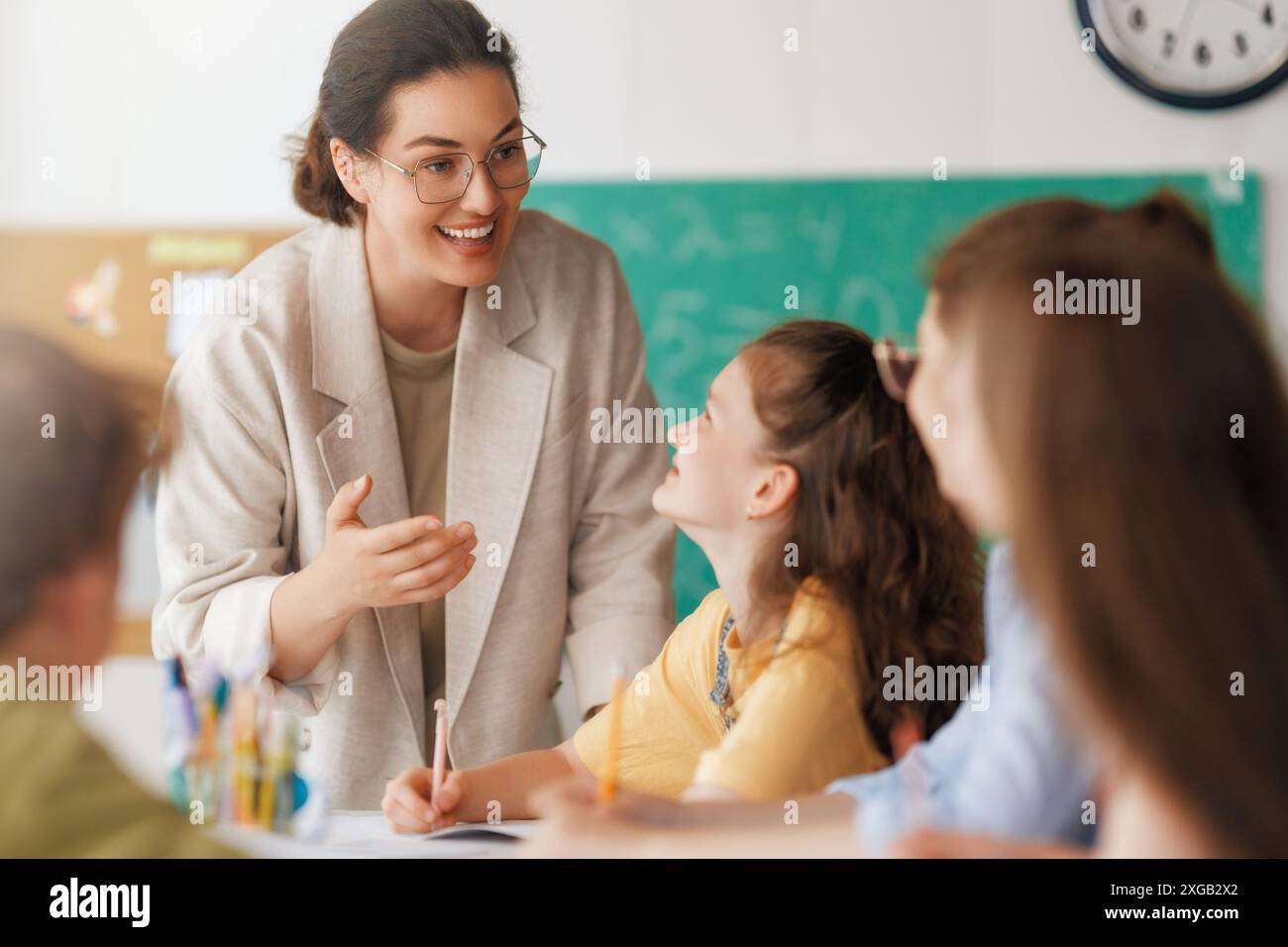 Happy kids and teacher at school. Woman and children are talking in the ...
