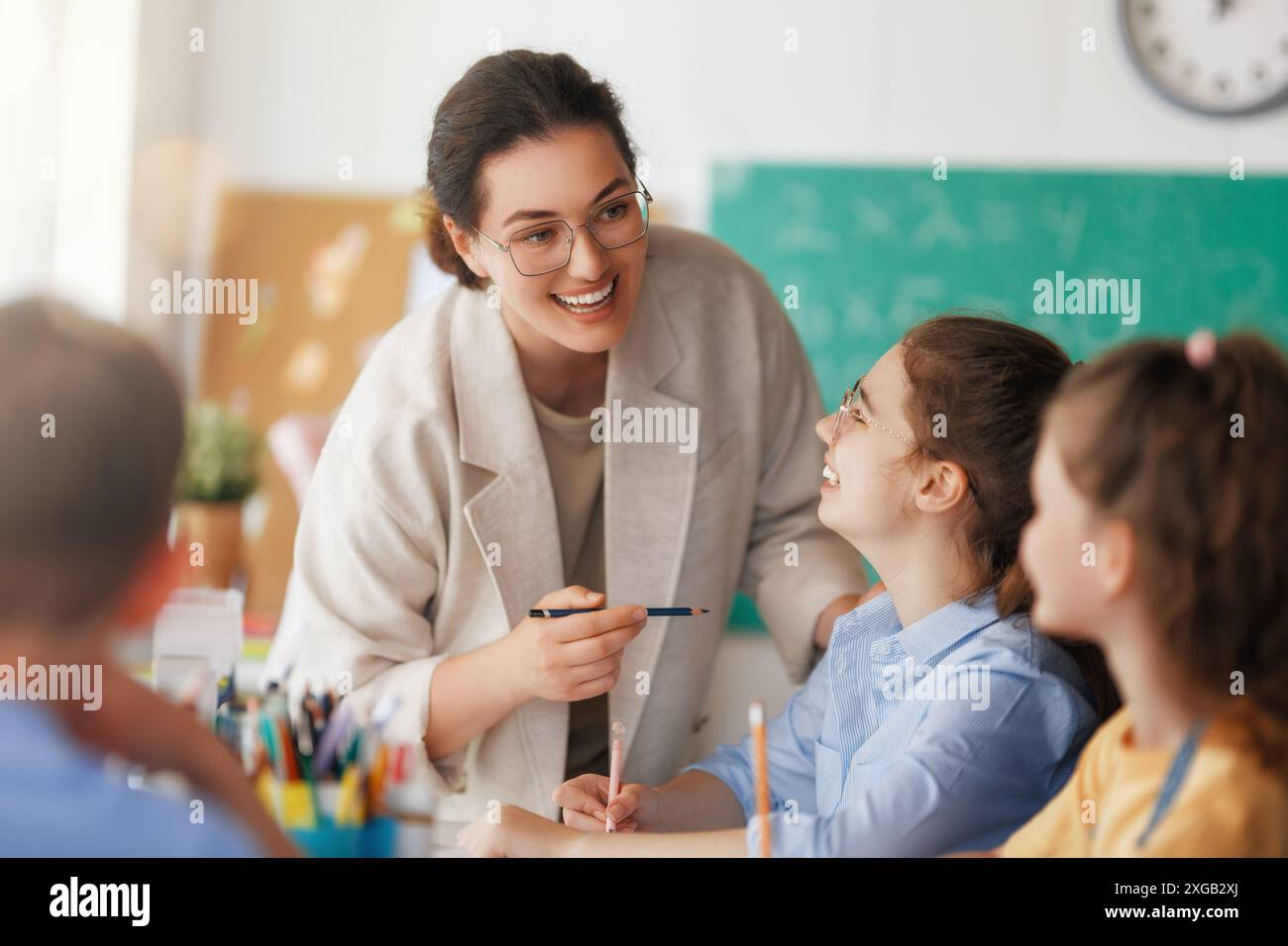 Happy kids and teacher at school. Woman and children are talking in the ...