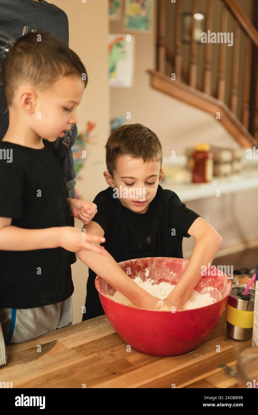 Brothers learning hand-on baking skills while mixing cookie dough Stock ...