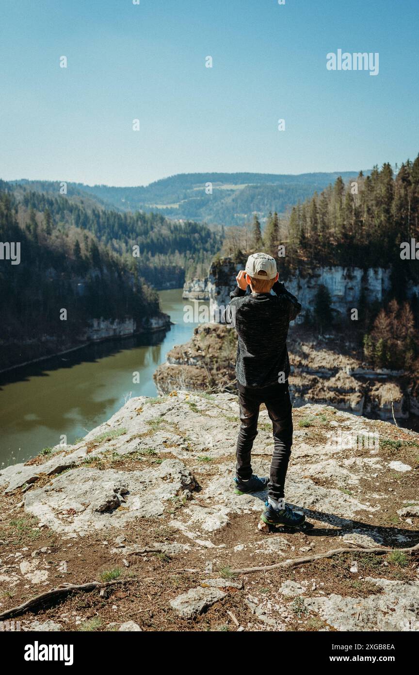 Boy hiking, watching River Doubs, Switzerland, from a cliff viewpoint ...