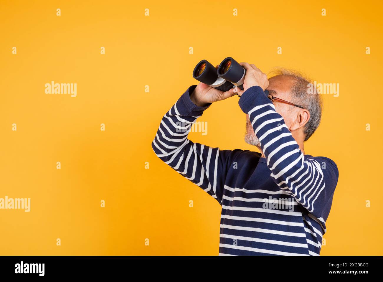 Portrait Asian smiling old man looking camera through binoculars studio ...