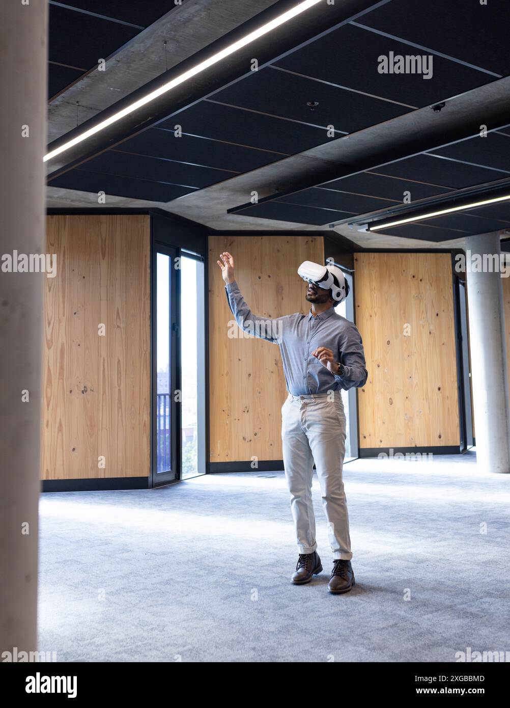 Using VR headset, man exploring virtual environment in modern office ...