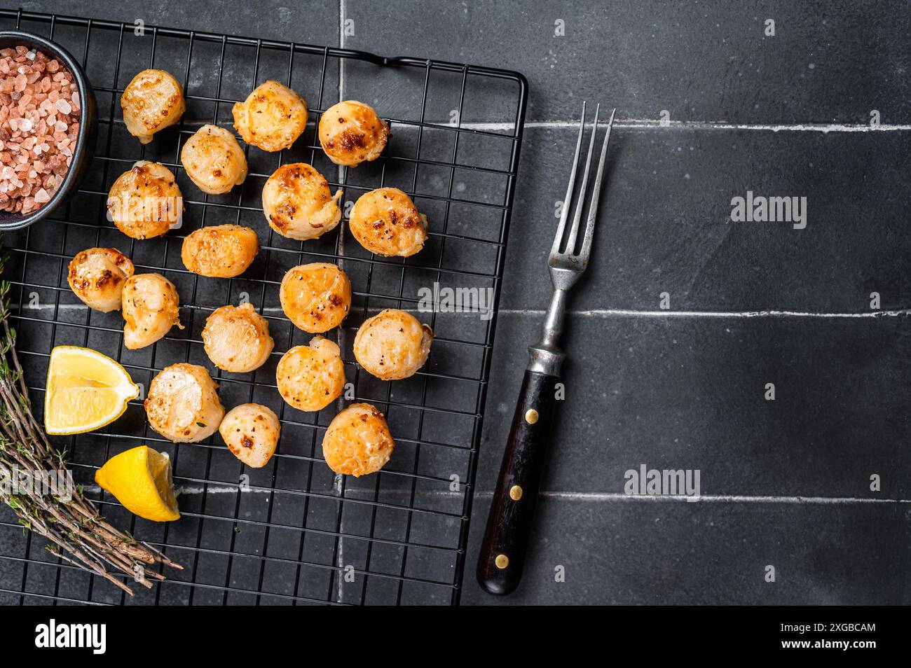 Grilled Scallops fillets on a rack. Black background. Top view. Copy ...