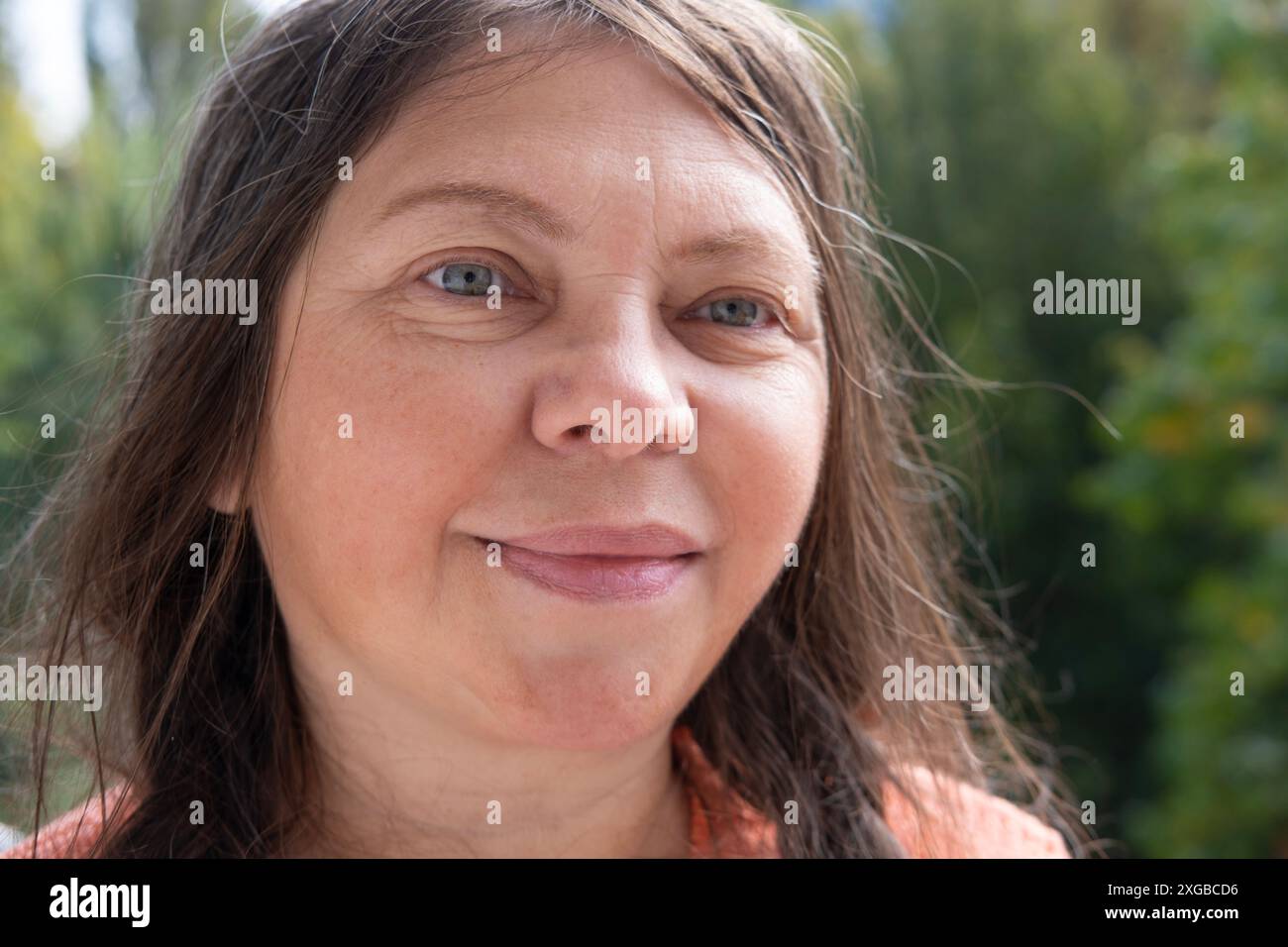 55-year-old woman smiles, her kind eyes looking happily, close-up face ...