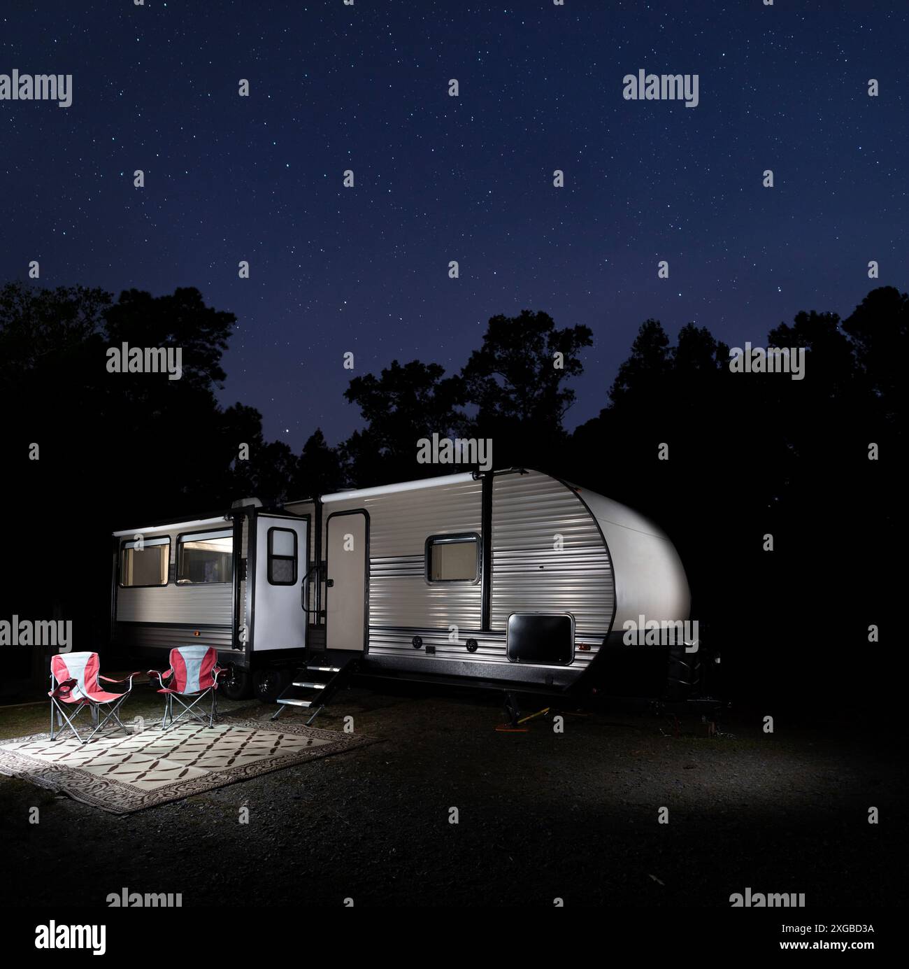 Stars above a camping trailer in a site surrounded by trees Stock Photo ...