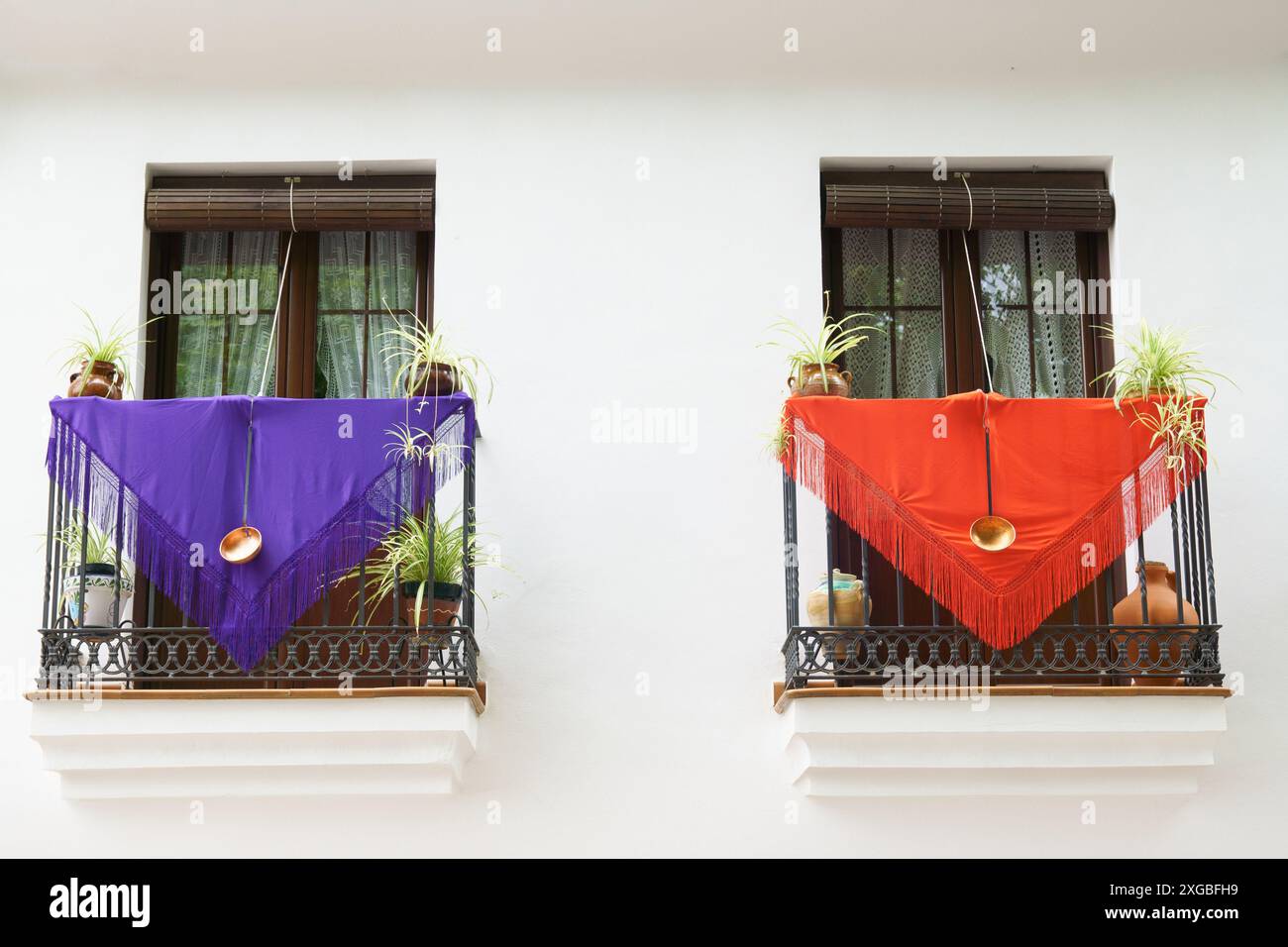 The Two balconies with colorful drapes, plants, and pots on a white ...