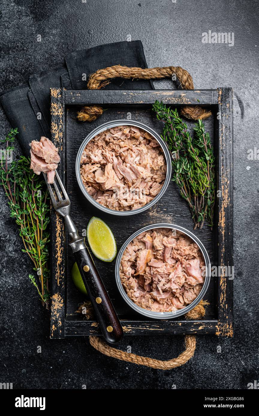 Open Can with Preserved tuna fillet meat. Black background. Top view ...