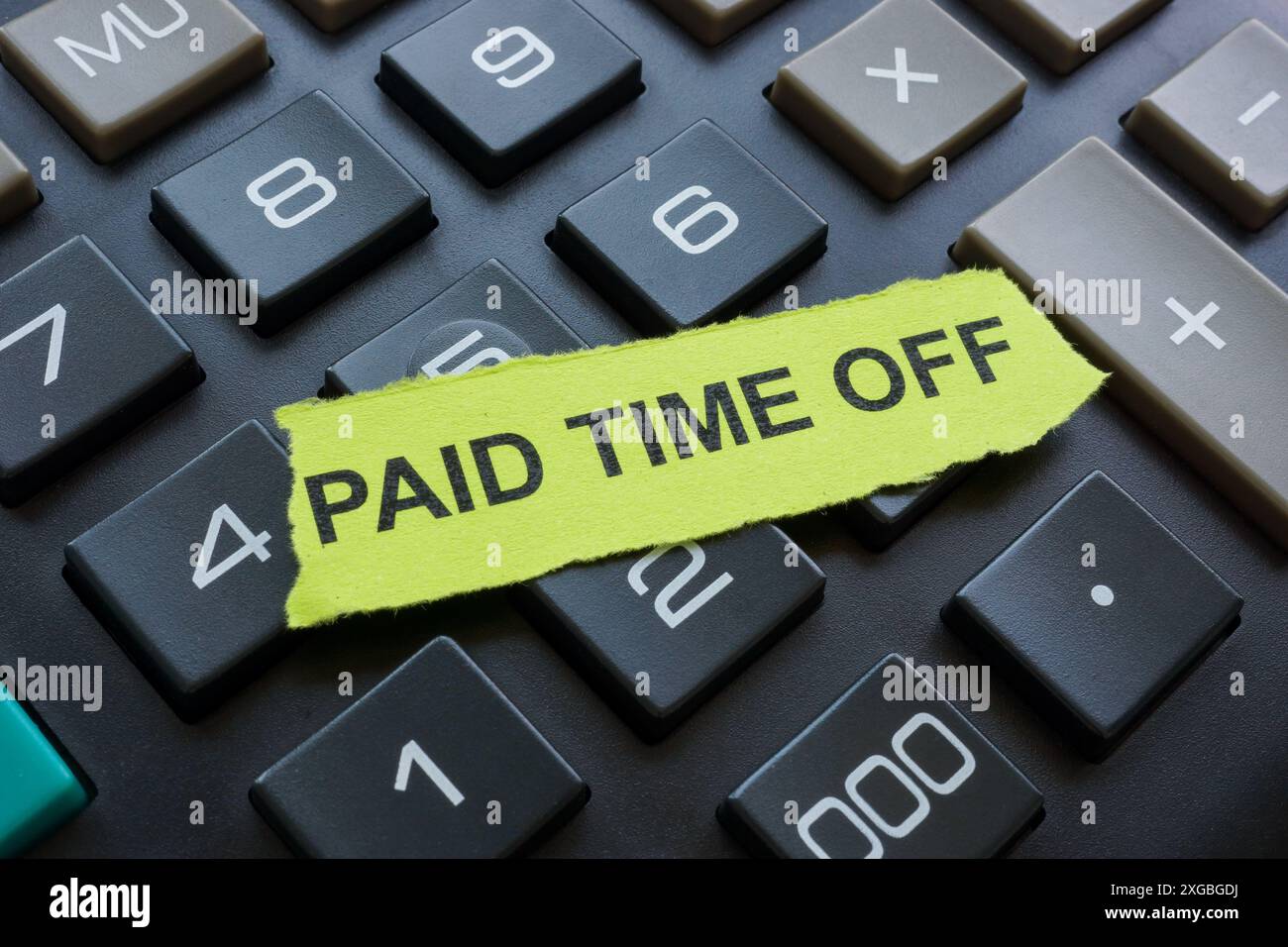 A piece of paper with words paid time off is lying on the calculator ...