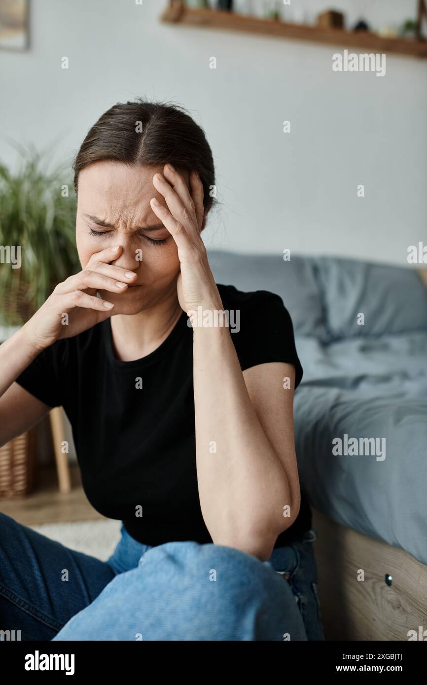 Middle-aged woman in distress, hands on face, sitting on floor Stock ...