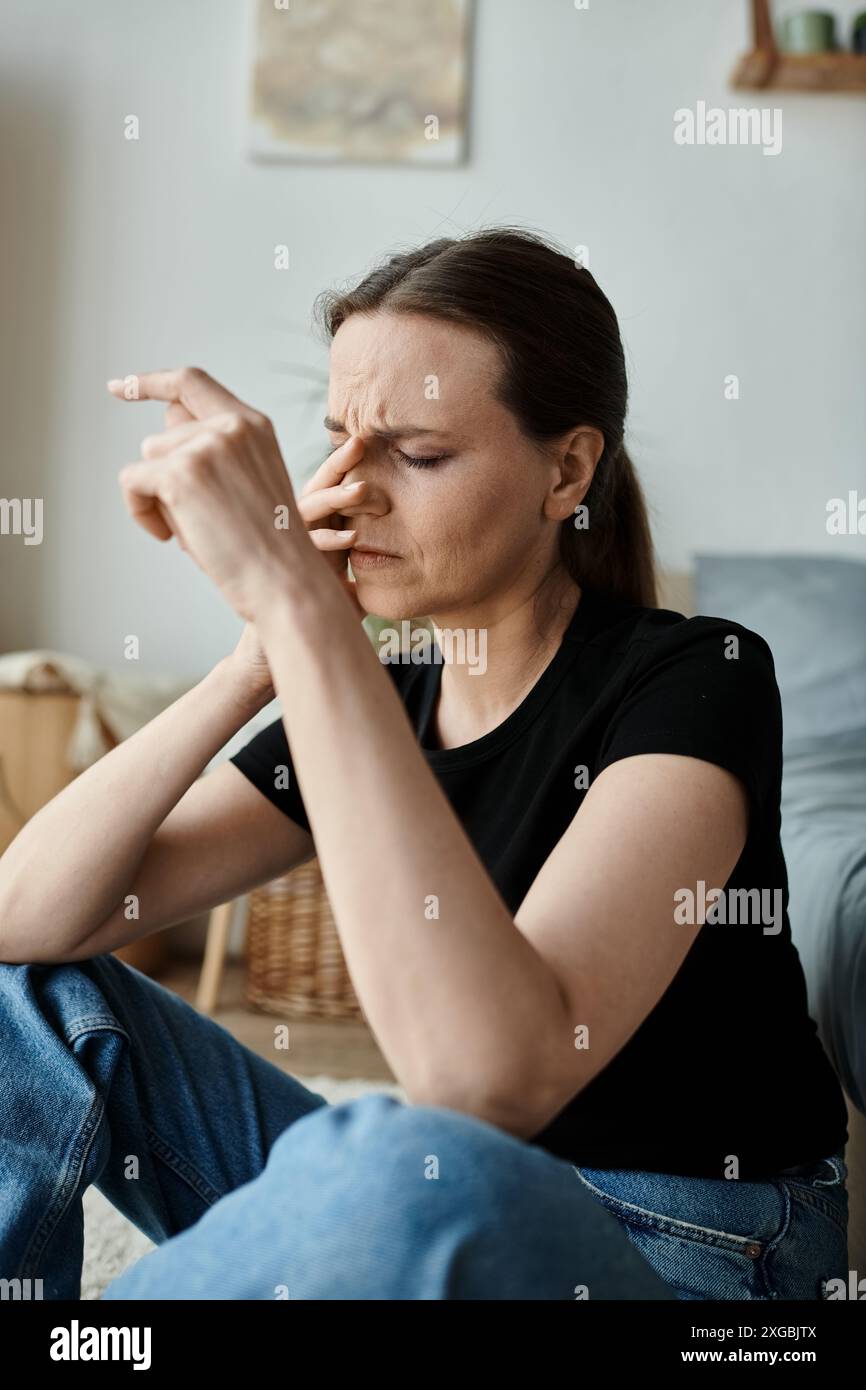 Middle-aged woman sitting, deep in thought, with finger on nose Stock ...