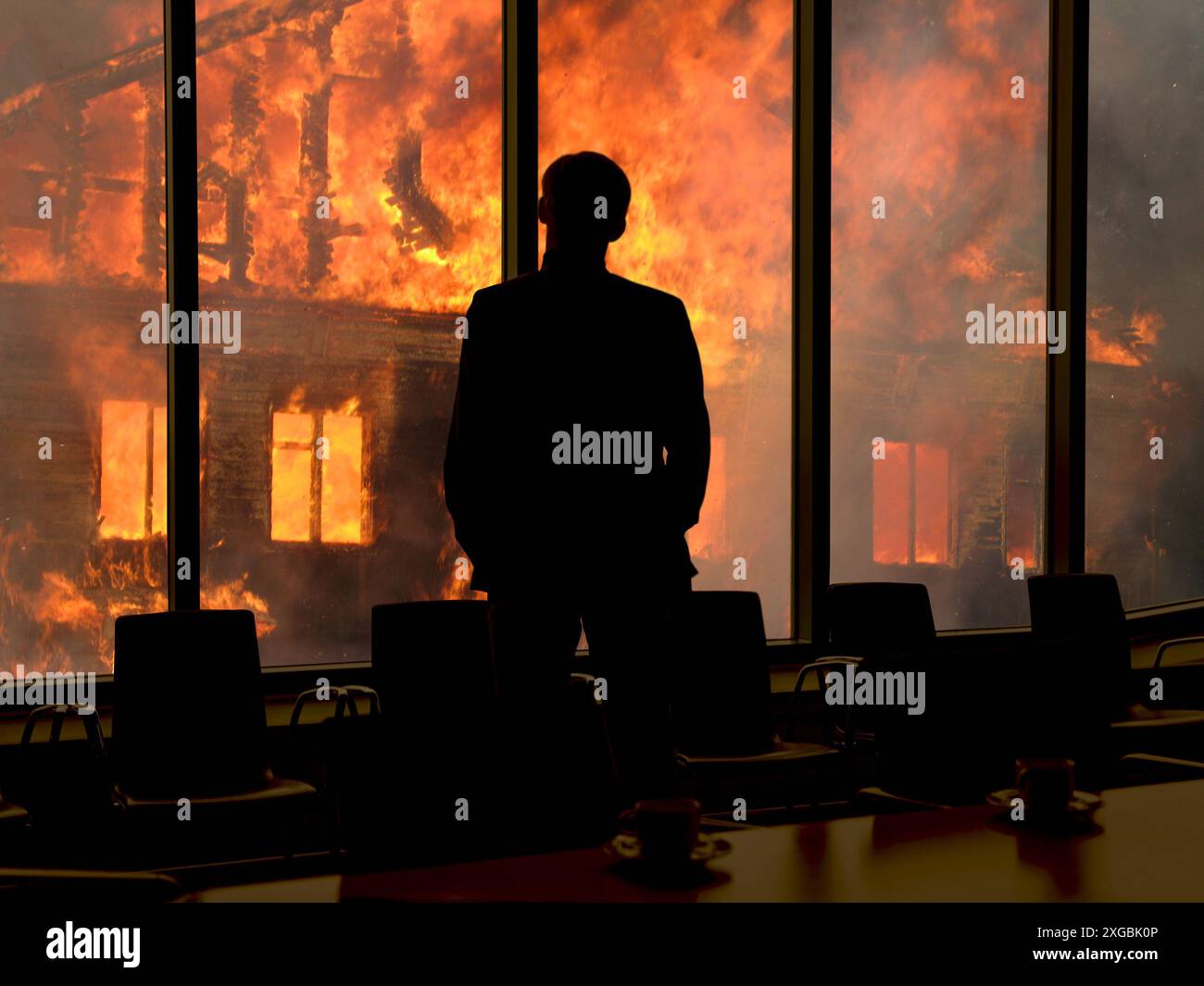 Businessman looking through thw window at burning house. Big wooden ...