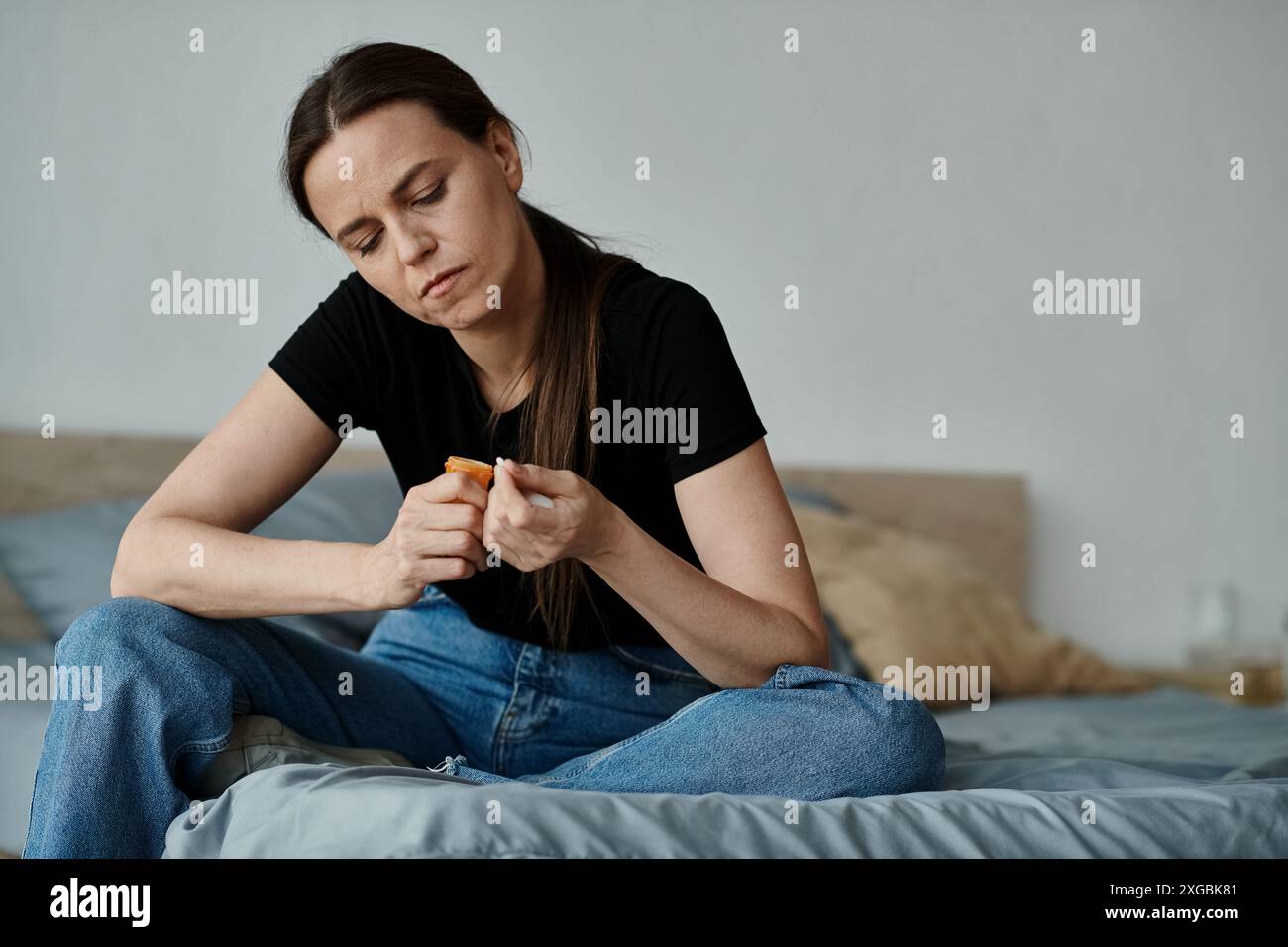 Middle-aged woman sitting on bed, contemplating life Stock Photo - Alamy