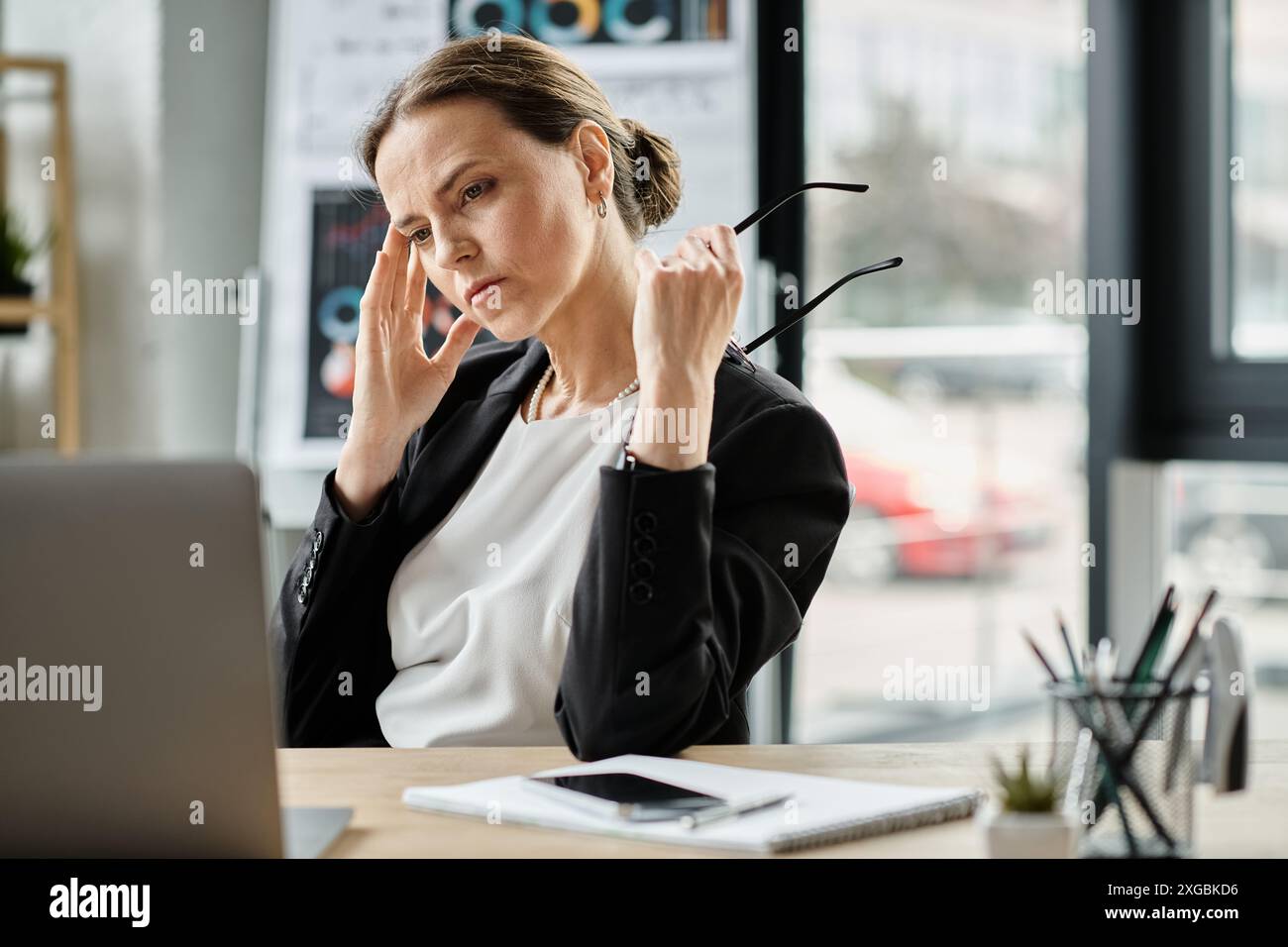 A woman sits at a desk with her eyes closed, finding peace in the midst ...
