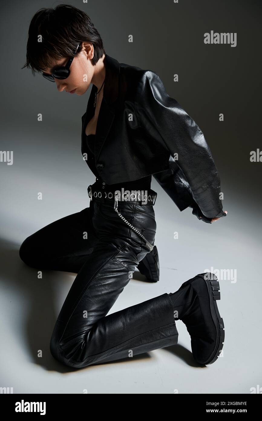 Stylish young woman in black leather pants crouching down Stock Photo ...
