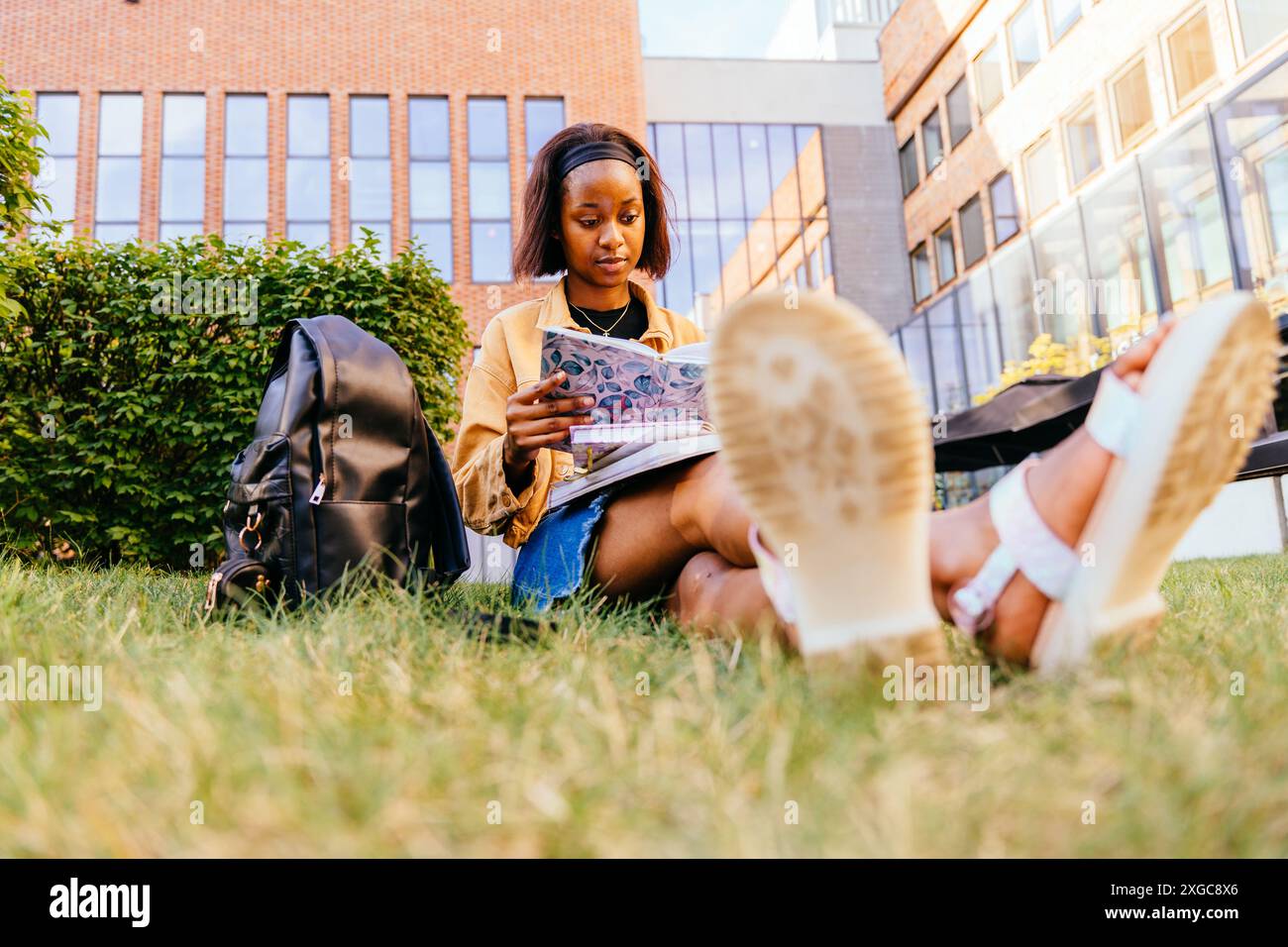 Adorable young African American woman reading a good book while ...