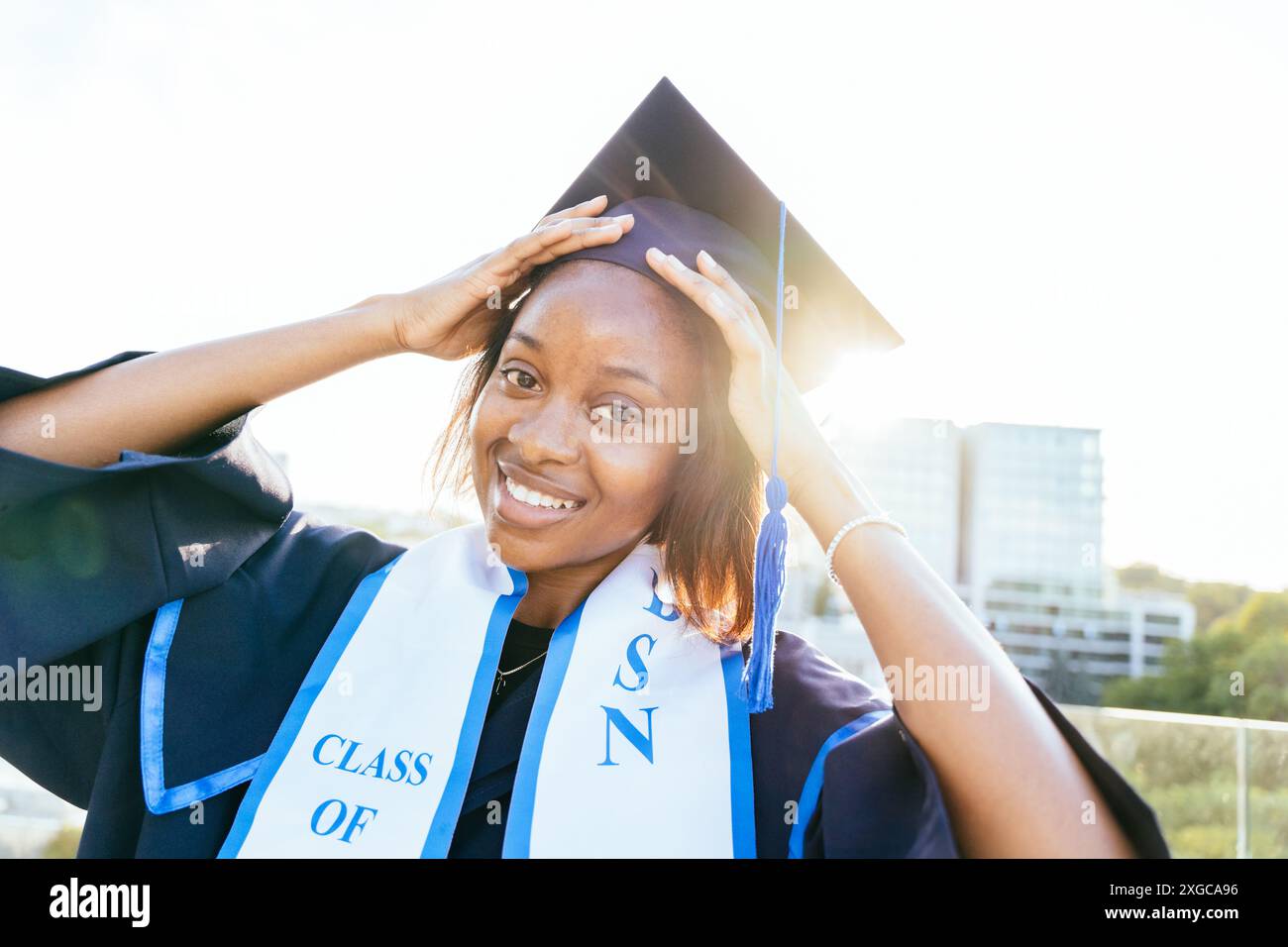 Portrait of cheerful Black woman in a graduation gown Stock Photo - Alamy