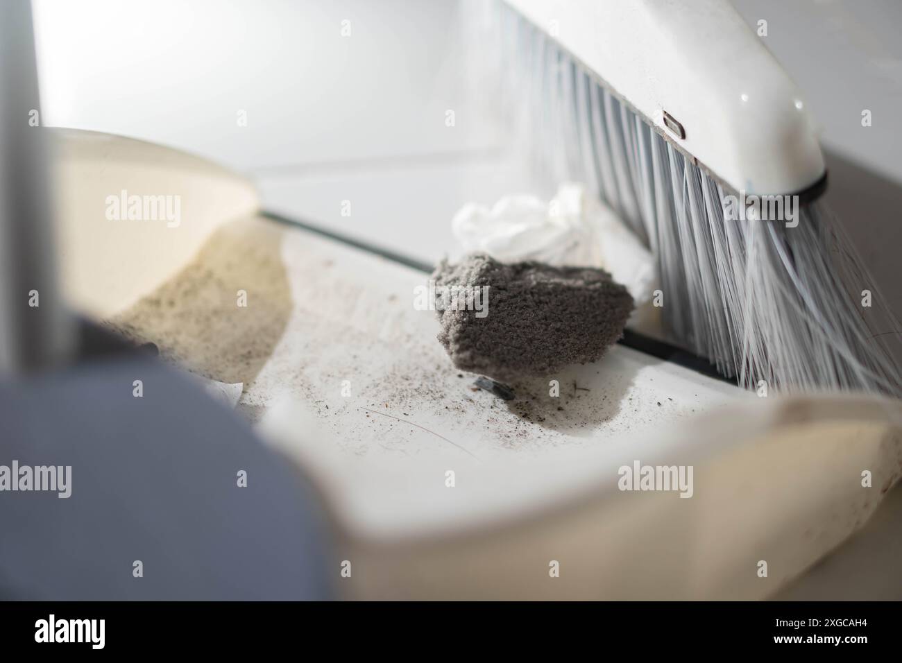 Close-up of a broom sweeping dust and debris into a dustpan. The ...