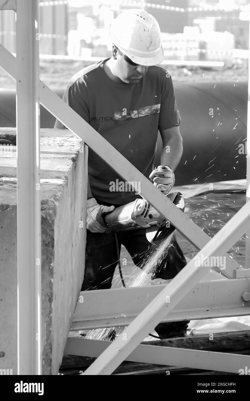 A grayscale vertical of Tradesman working with an angle grinder on a ...
