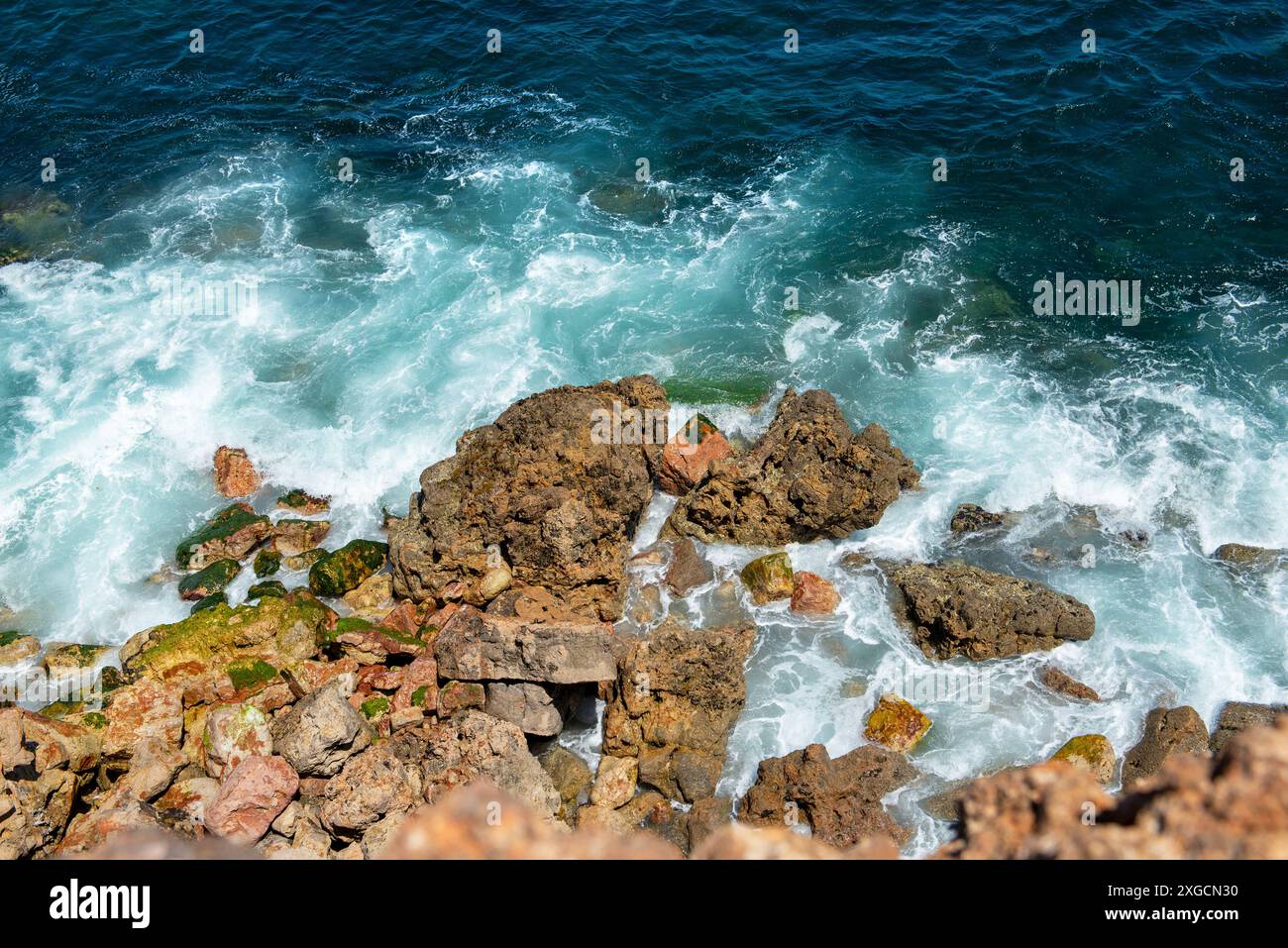 view from the top of the sea with waves hitting the rocks forming foam ...