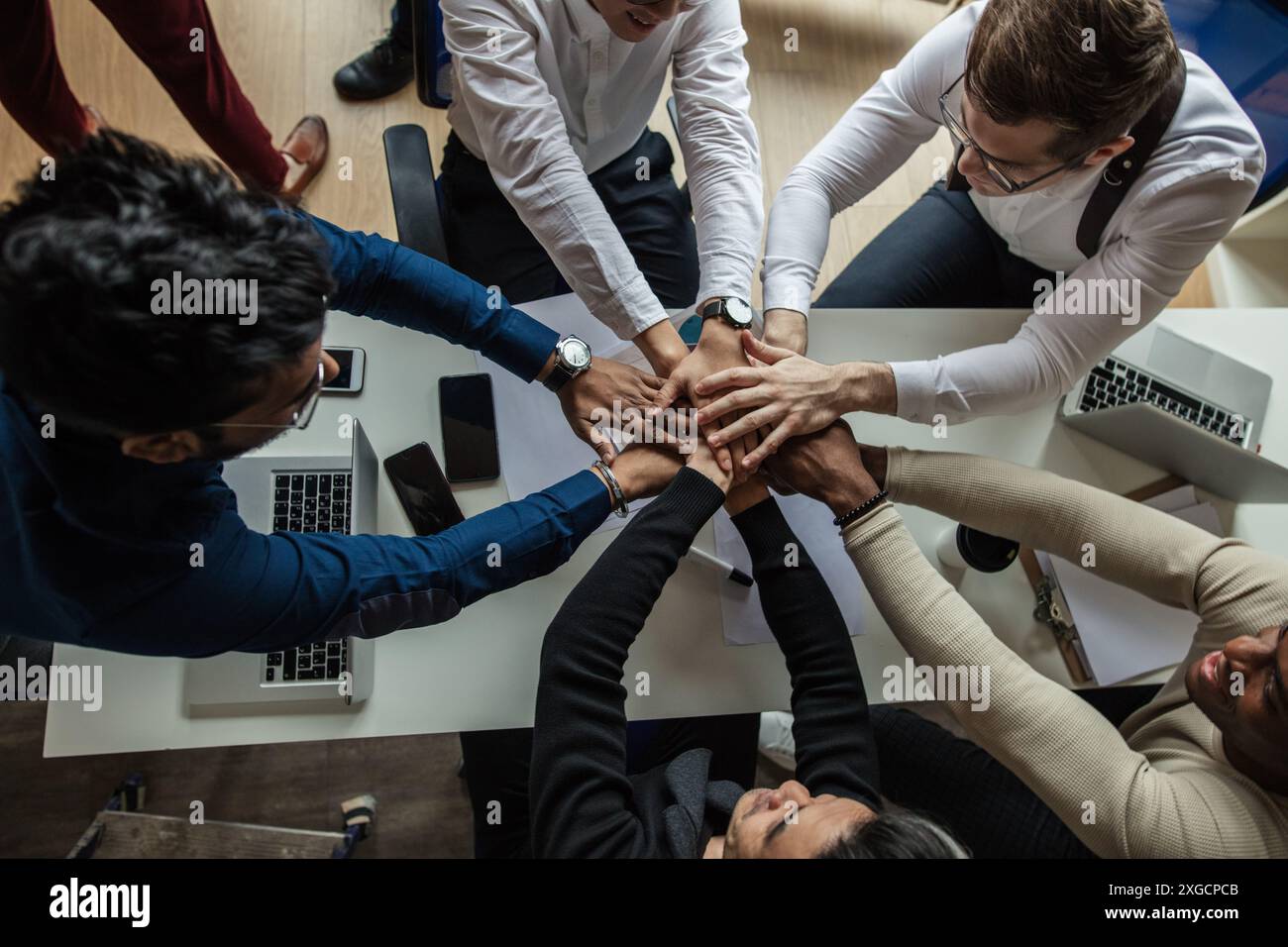 Top view of businessmen standing and stacking hands over table in a meeting with copy space at ...