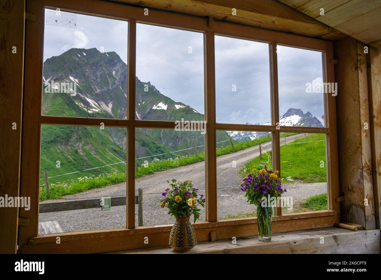 view through the window of a alpine wooden farm in the mountains from ...