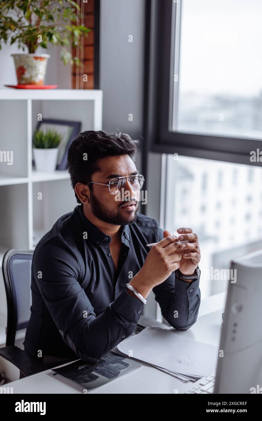 Portrait of young Indian professional lowyer sitting at his desk in the ...