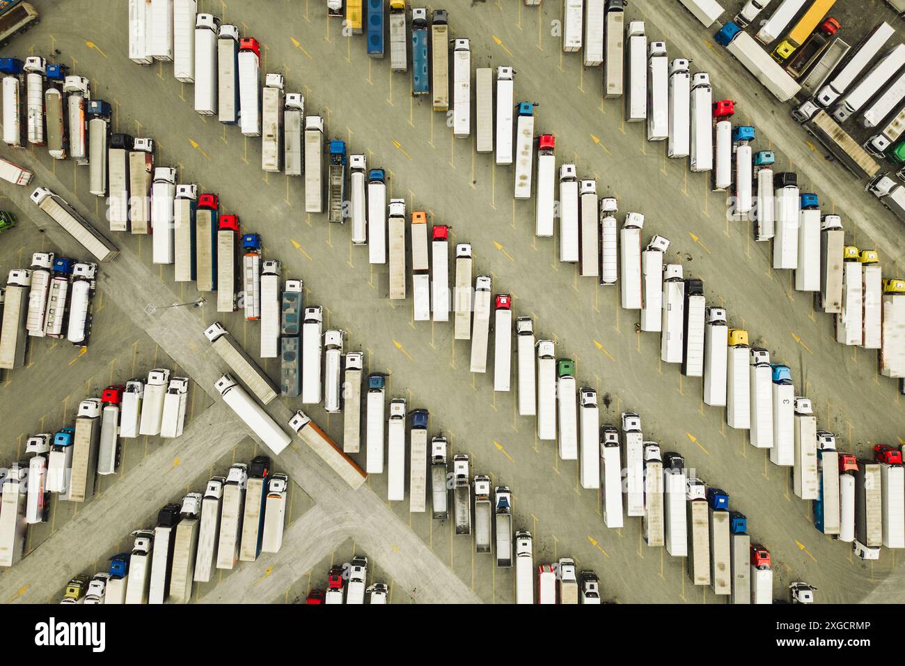 Aerial fly over lines of lorry trucks stand symmetrical in parking lot ...