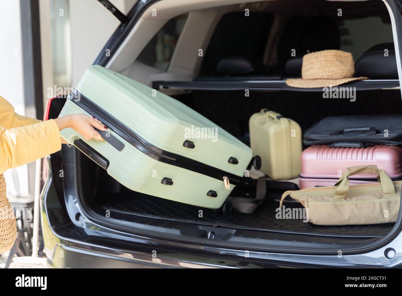 Woman loading suitcase into car trunk, preparation for trip. Open car ...