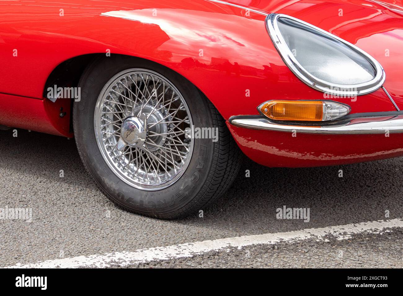 Detail of an E Type Jaguar with red paintwork, showing the wire wheels ...