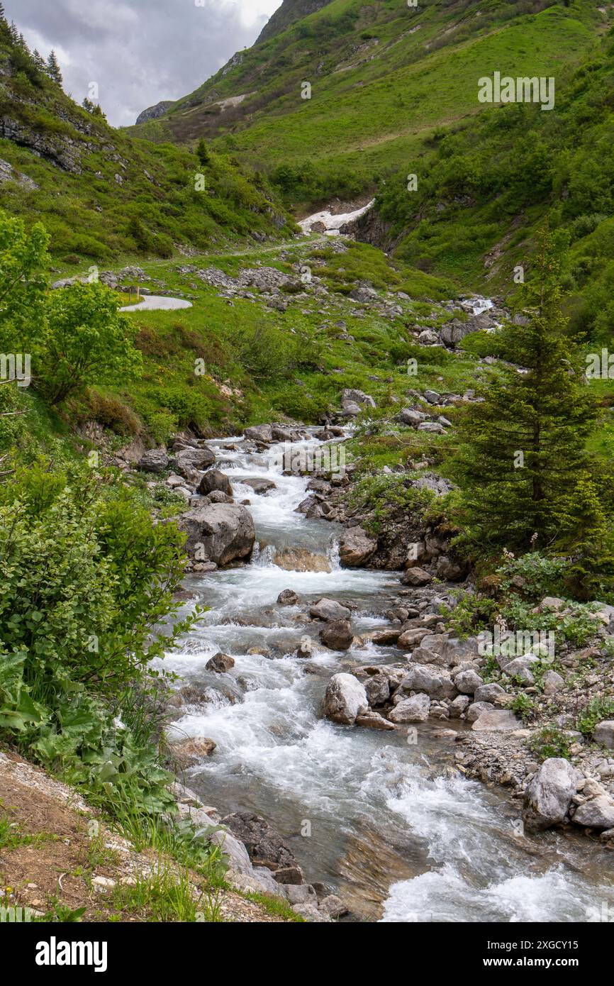 Water from snow melting in the Alps of Vorarlberg flows down the stream ...
