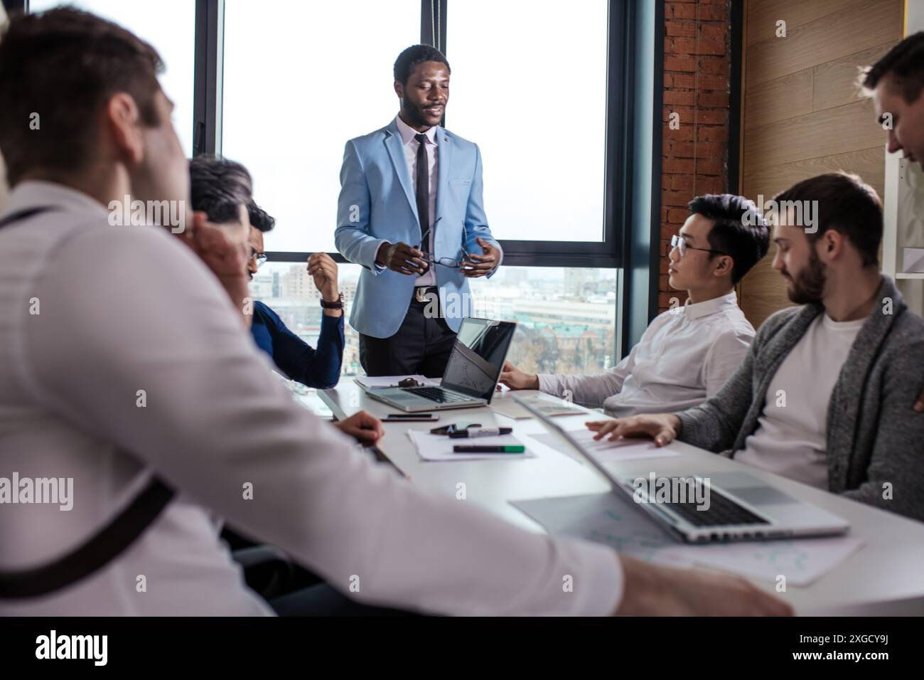 Businessman in blue formal suit standing and leading business meeting ...