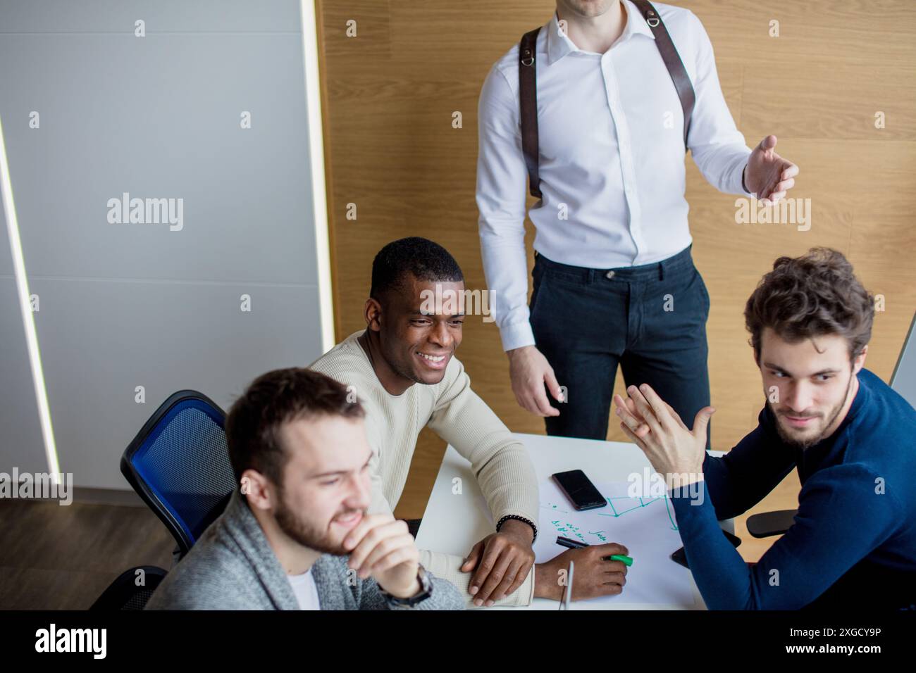 Positive young multiracial male team sitting at conference meeting ...