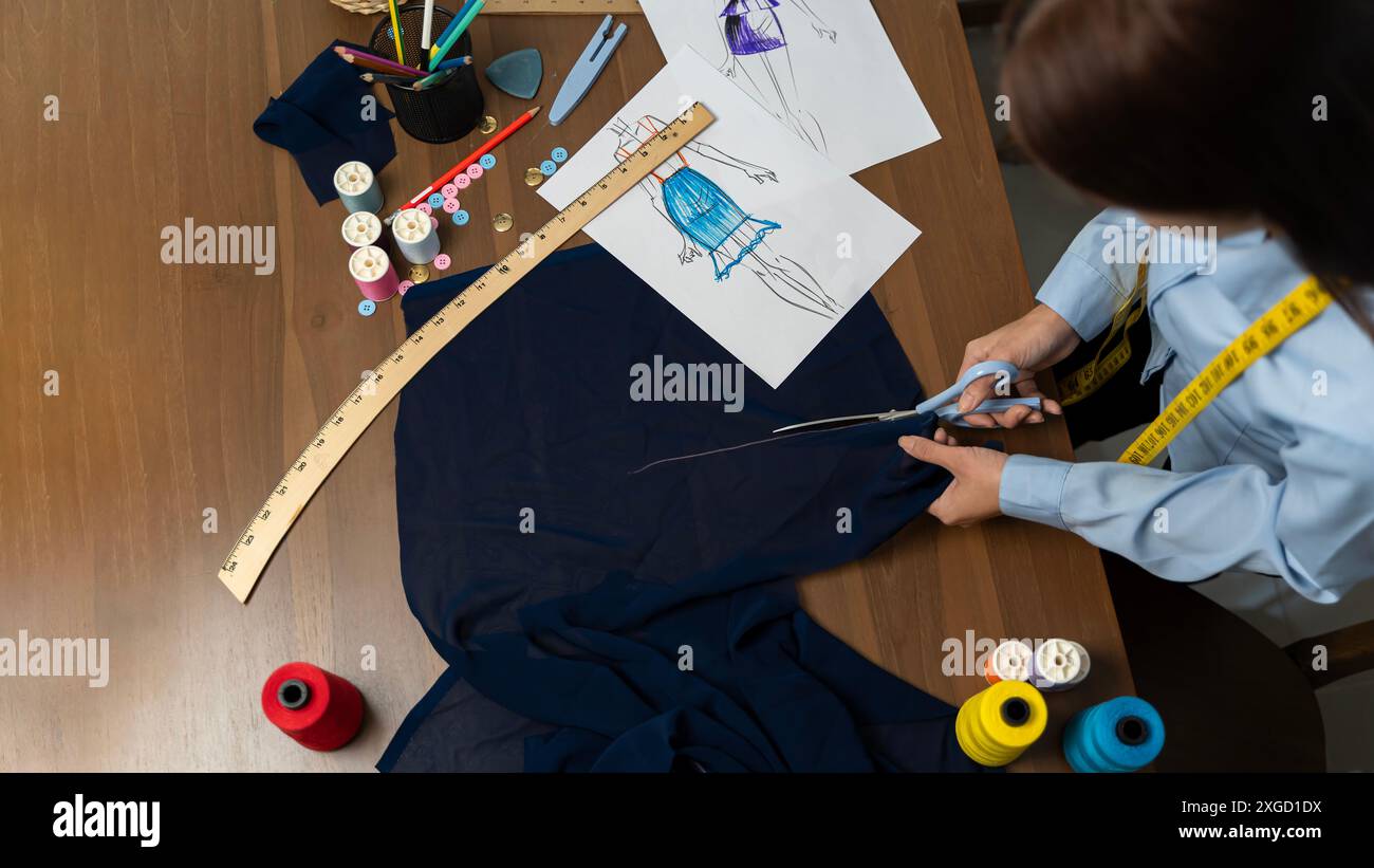 A tailor cuts a dress on a sketch line with a sewing machine, a fashion ...