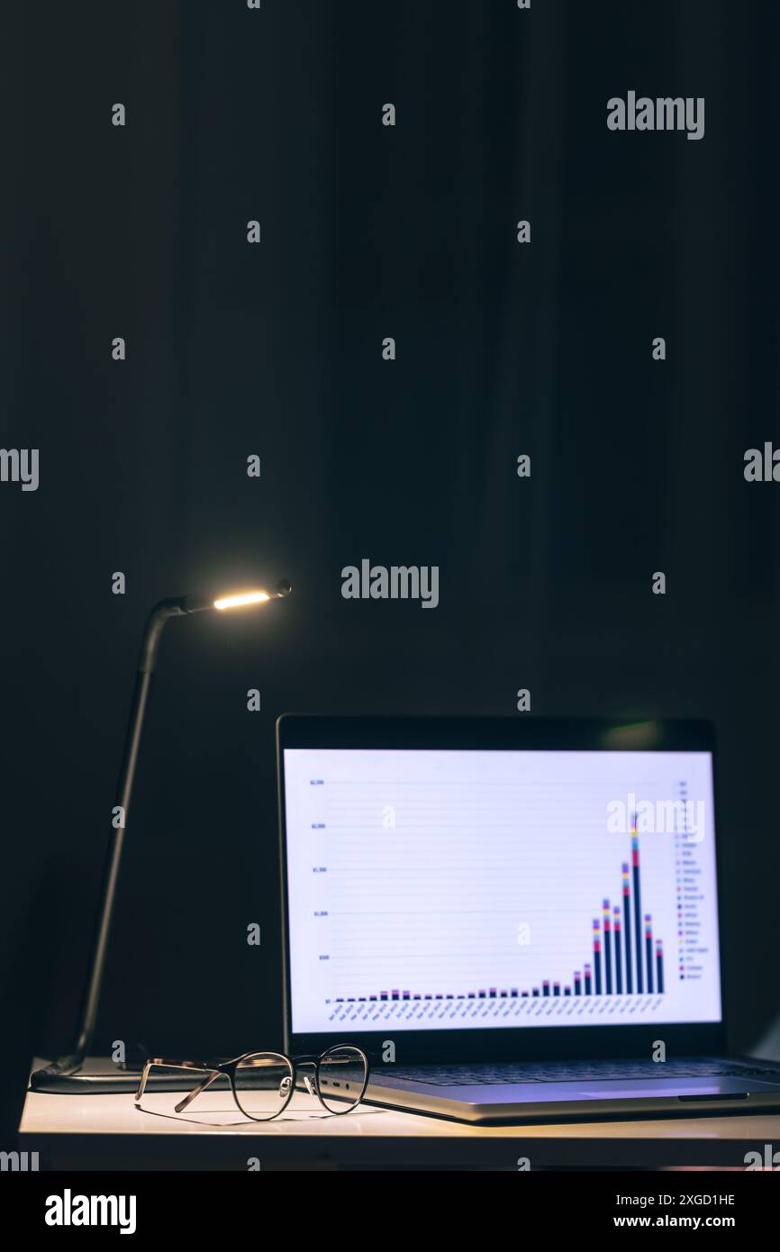 Computer in a dark room with graphs on the screen Stock Photo - Alamy