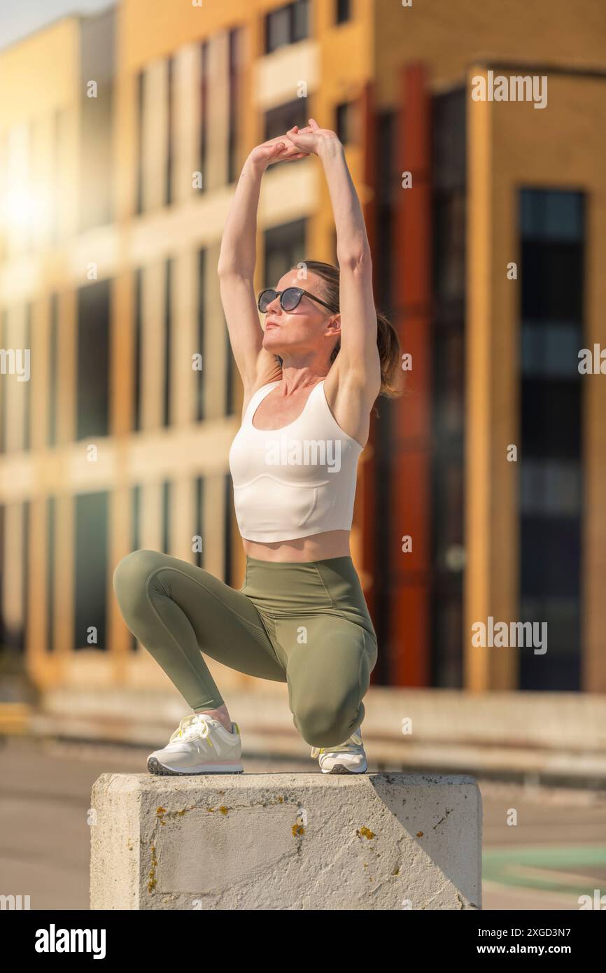 sporty woman doing stretching exercises in the sun, urban fitness ...