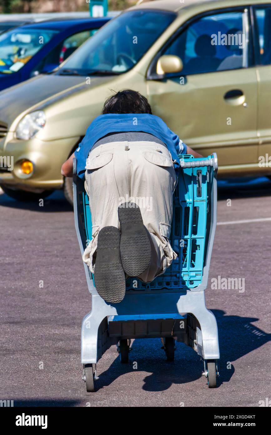 boy teenager playing and riding ,pushing a trolley in the parking lot ...