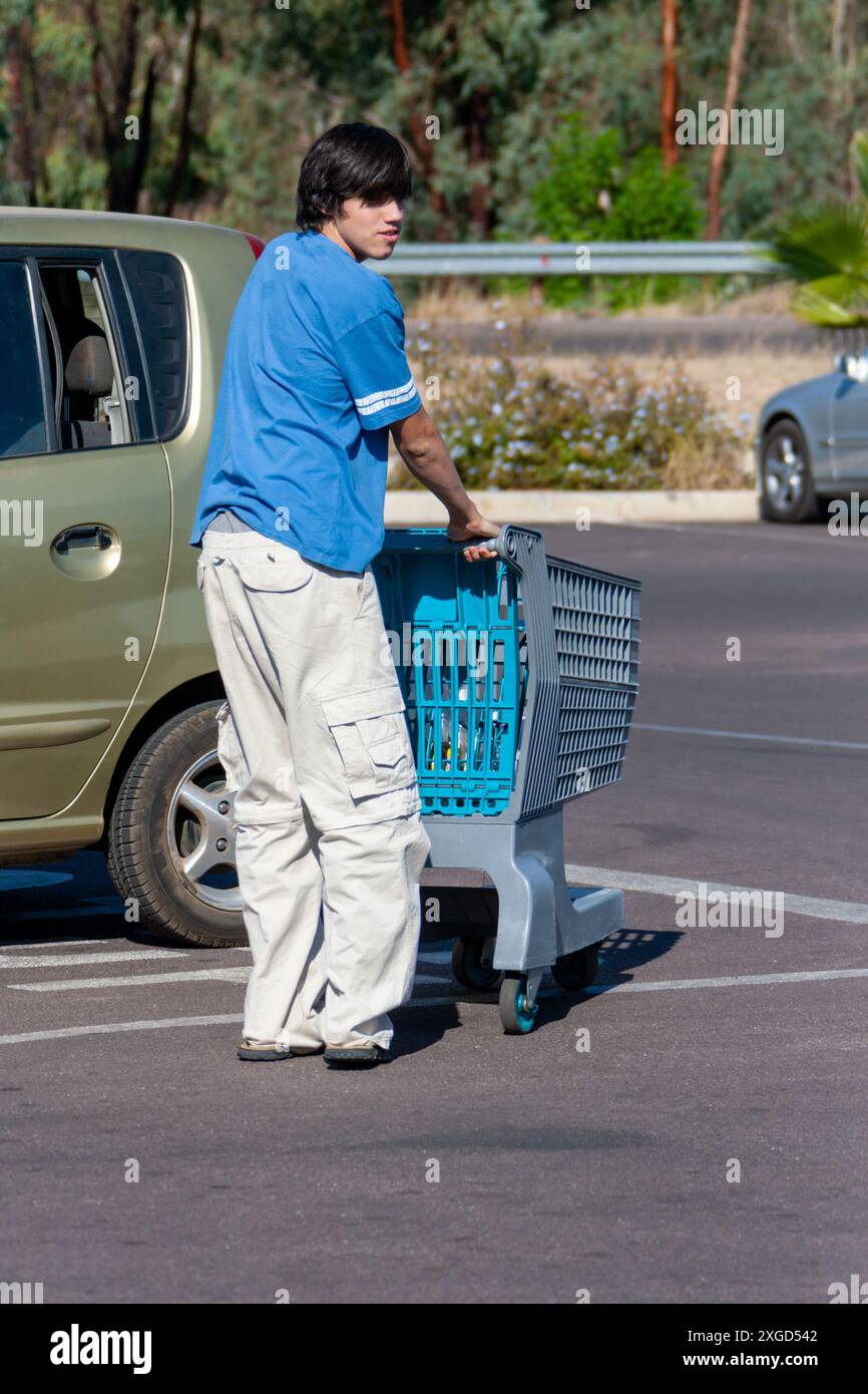 boy teenager pushing a trolley in the parking lot Stock Photo - Alamy