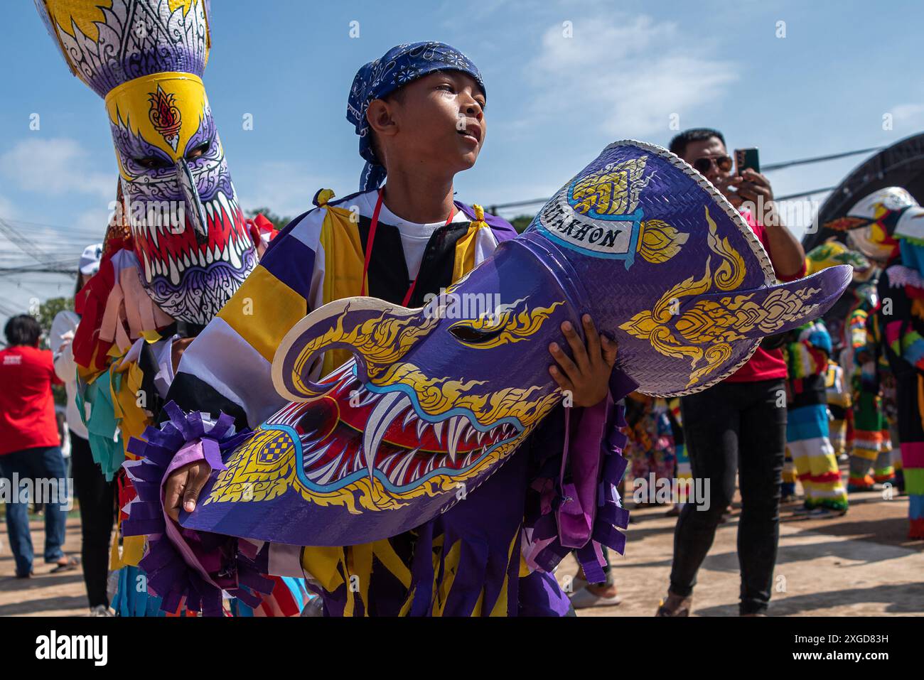 A kid holds a ghost mask while dancing during the festival. The "Phi Ta ...
