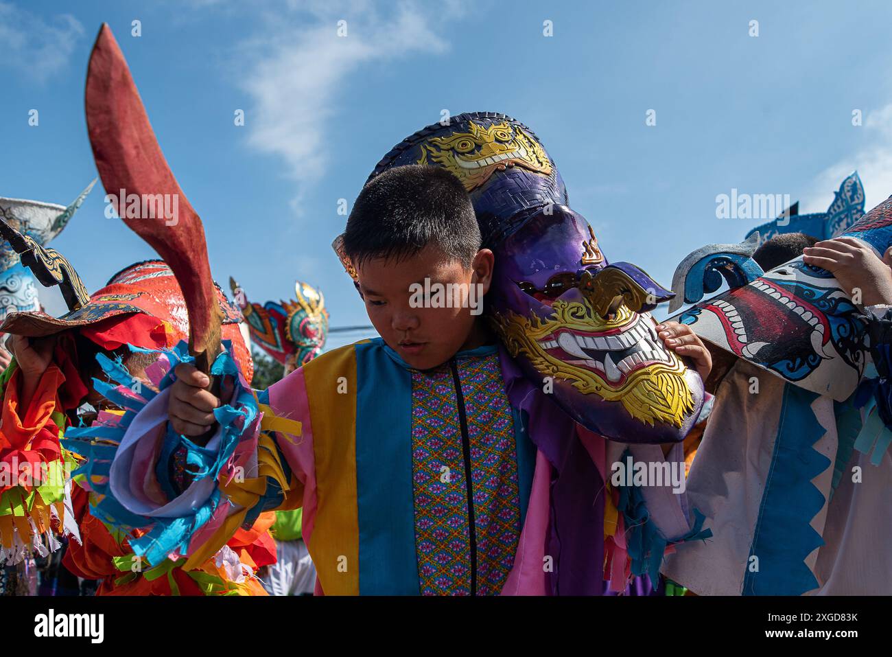 A kid holds a ghost mask while dancing during the festival. The "Phi Ta ...