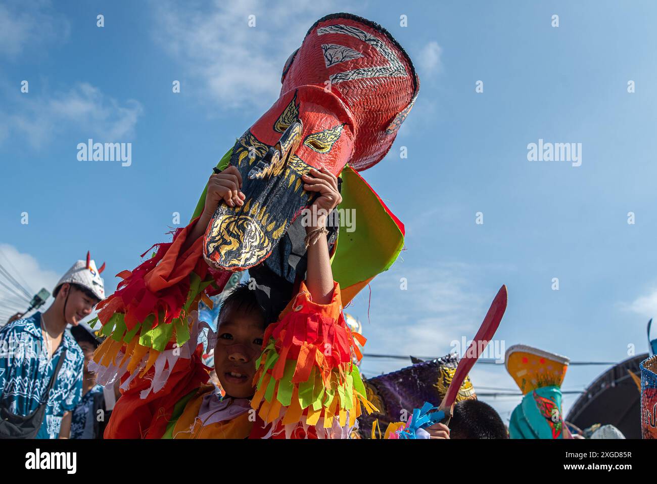 A kid holds a ghost mask while dancing during the festival. The "Phi Ta ...