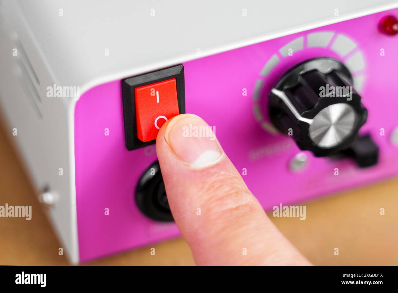 Pressing the red start switch of an electrical device with pink control ...