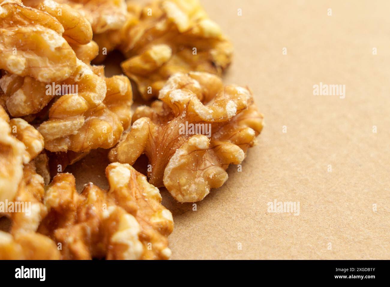 Walnut halves scattered on a brown paper surface close up. Raw healthy ...