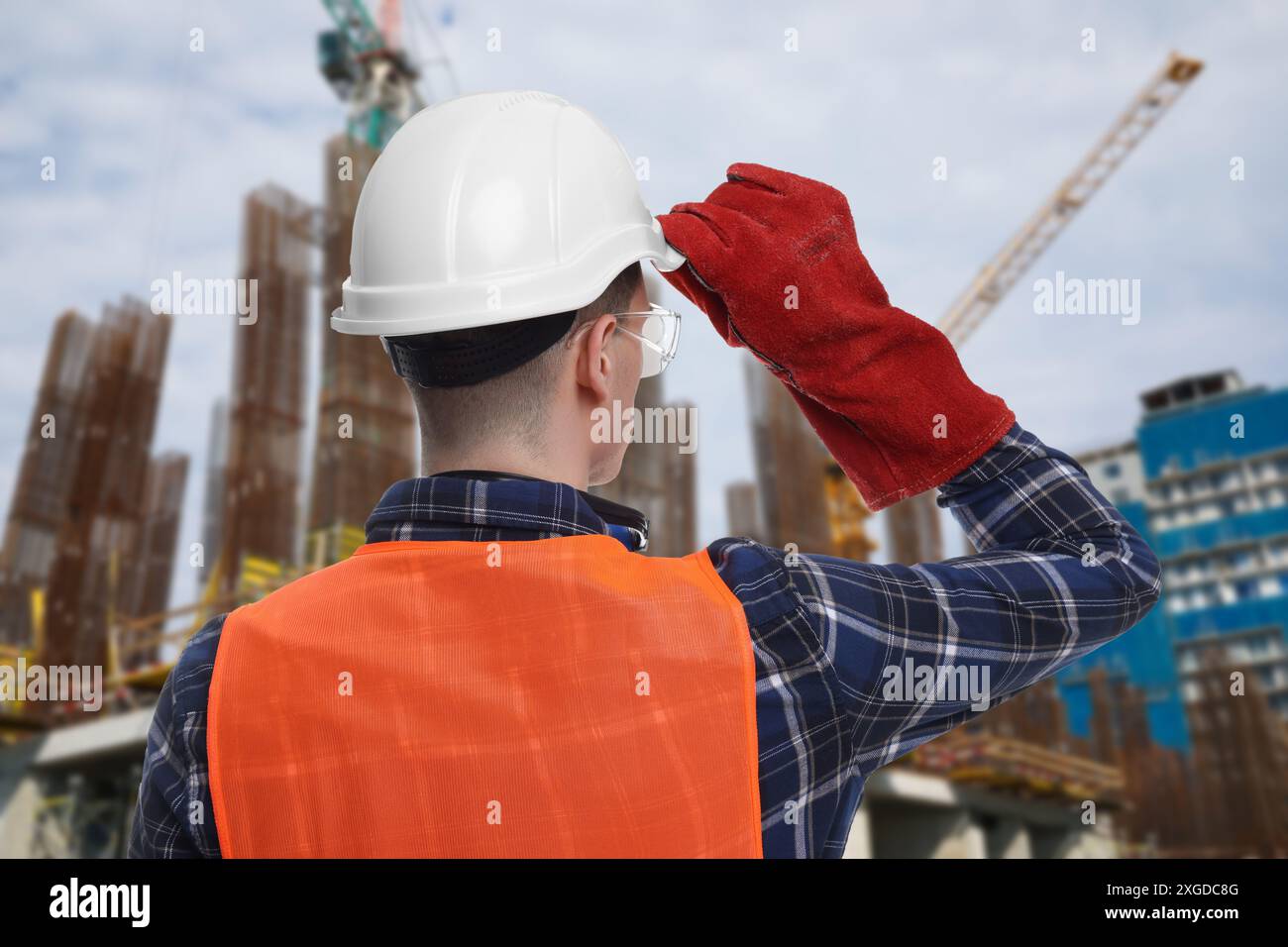 Young man wearing safety equipment at construction site, back view ...