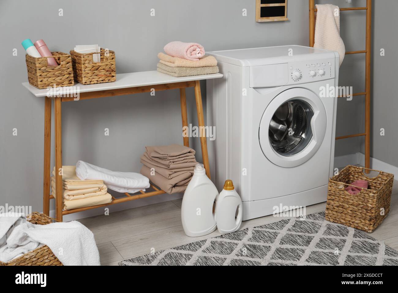 Washing machine, detergents, basket, laundry and storage bench indoors ...
