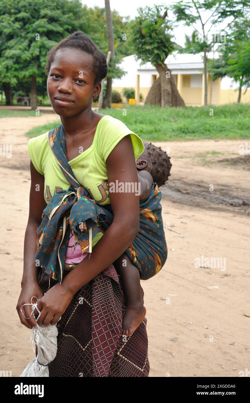 Young woman with baby on her back, New Mambone, Inhambane, Mozambique. African women use a ...