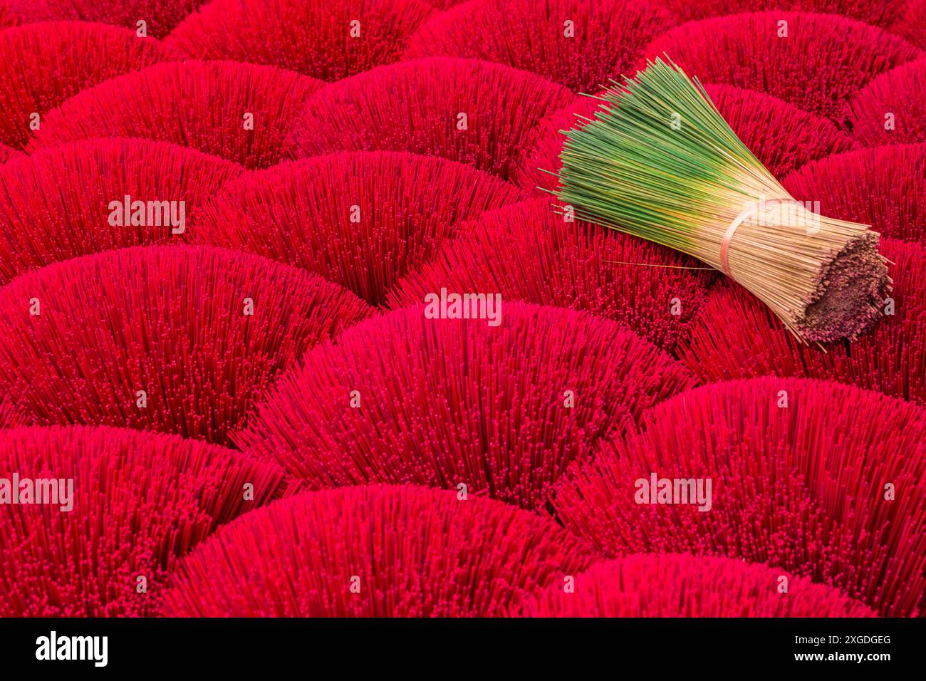Vibrant red incense sticks & bundle of green incense laid out on the ...