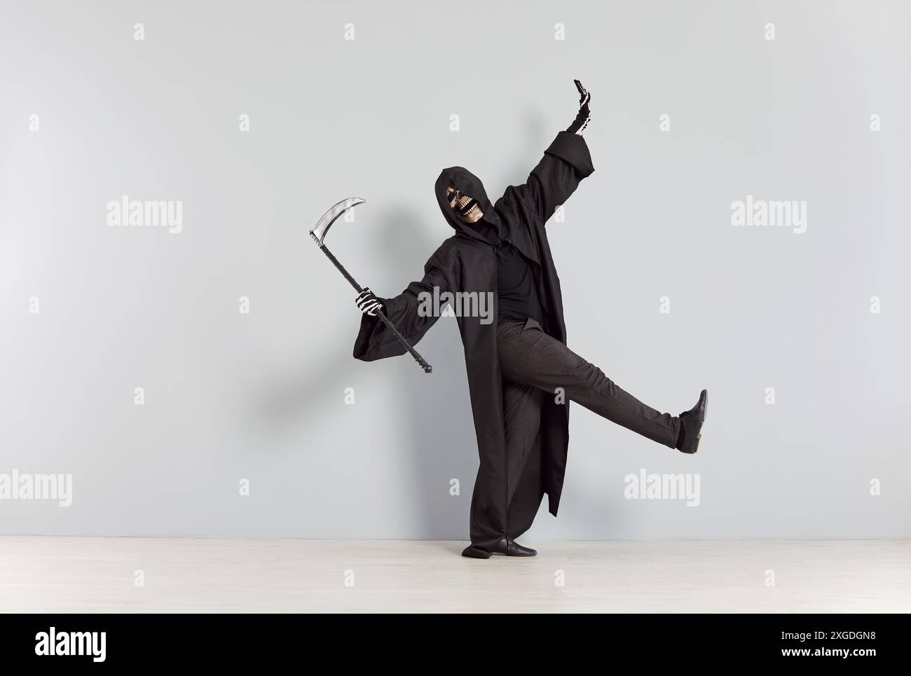 Man in grim reaper death costume having fun isolated on studio gray ...