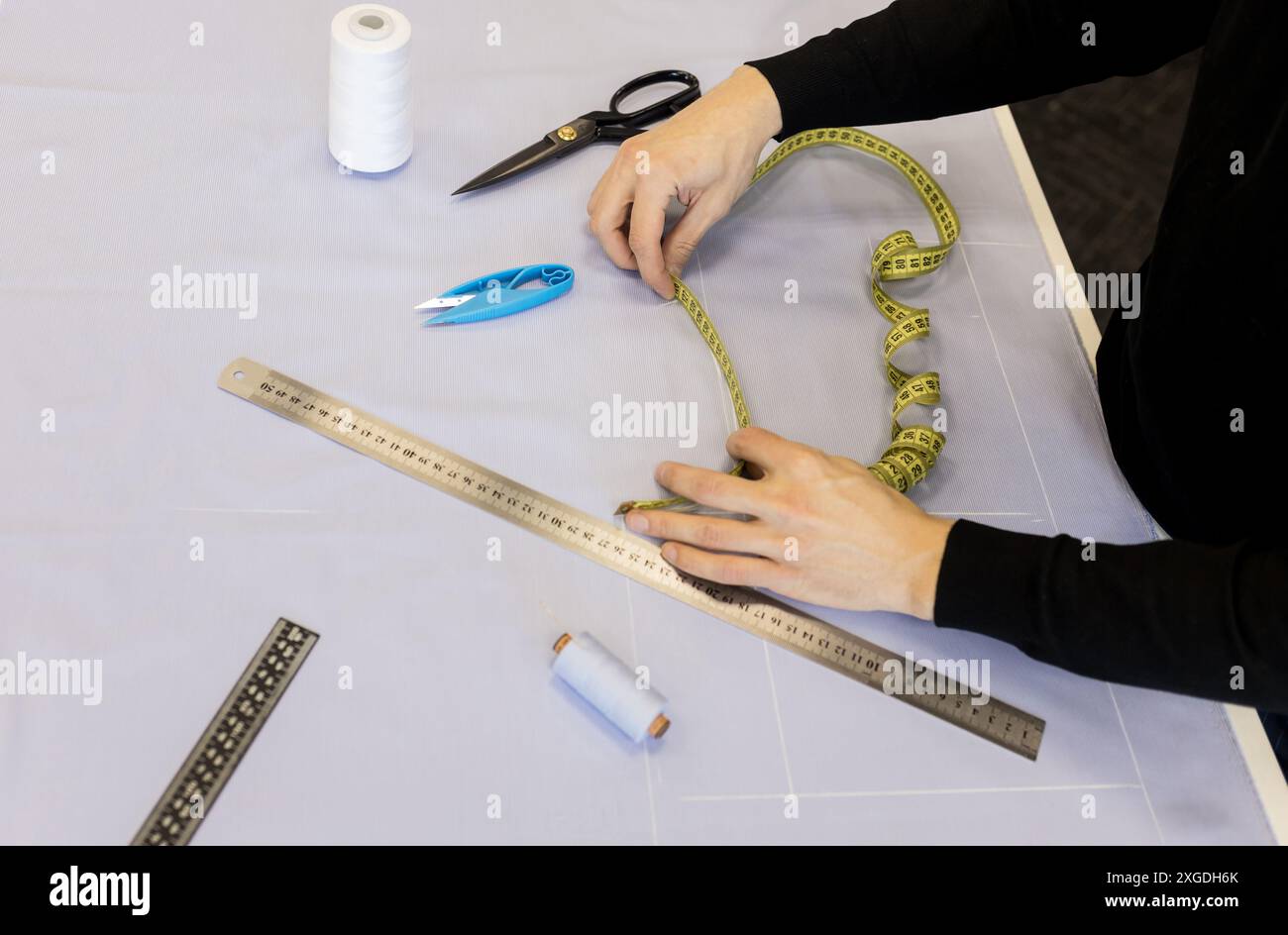 A male tailor works in an atelier with tape measure Stock Photo - Alamy