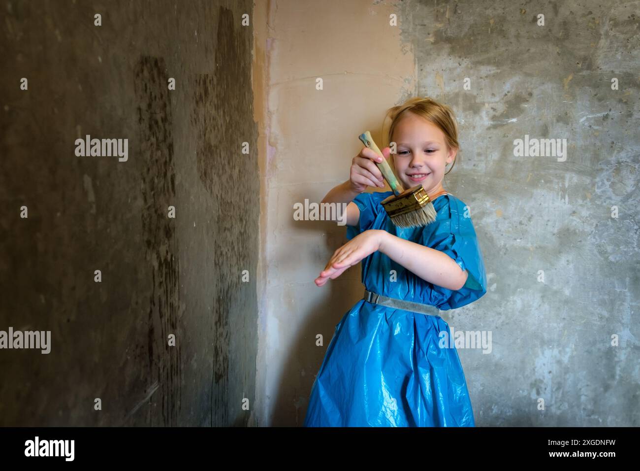 A powerful image of a 9-year-old girl in blue workwear painting a ...